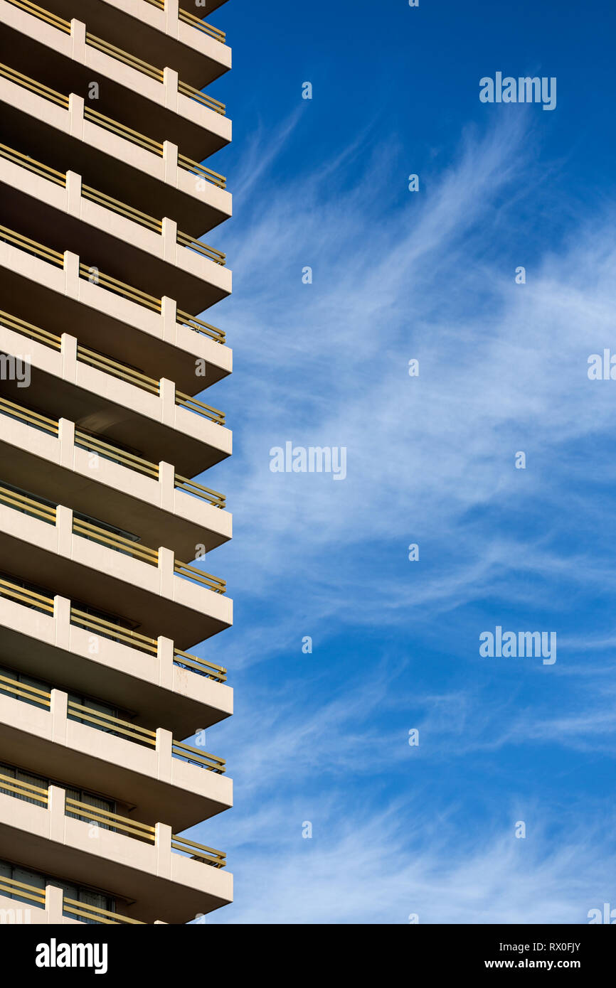 A section of a tall building with many floors stacked up and sky with ...
