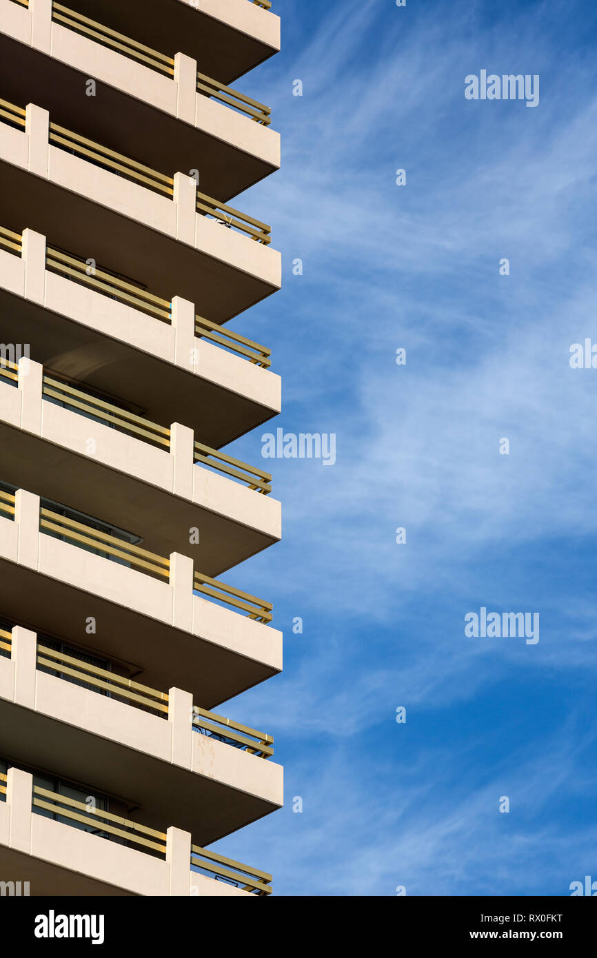 A section of a tall building with many floors stacked up and sky with ...