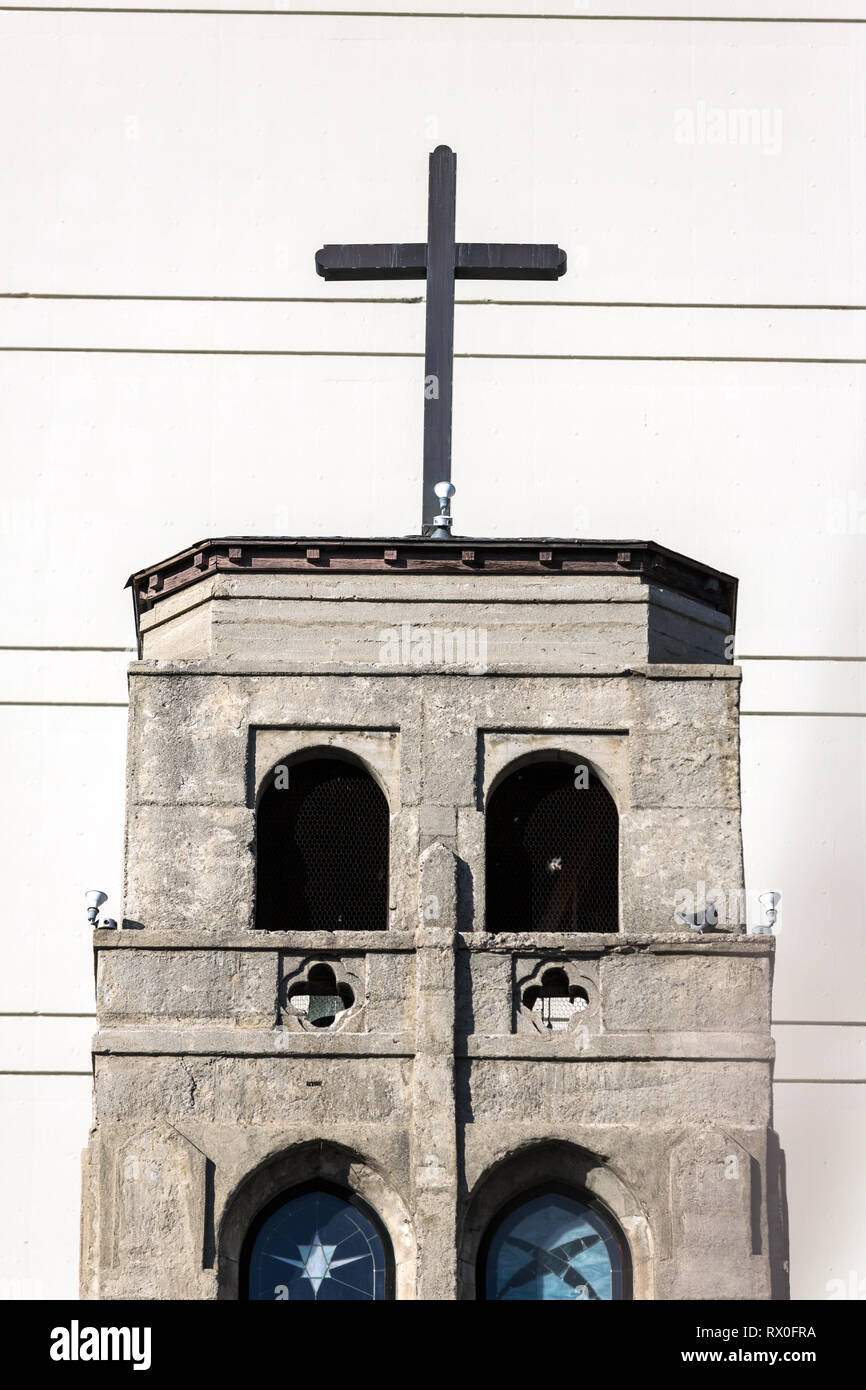 Cross rising from stone architecture on a church in front of a modern ...