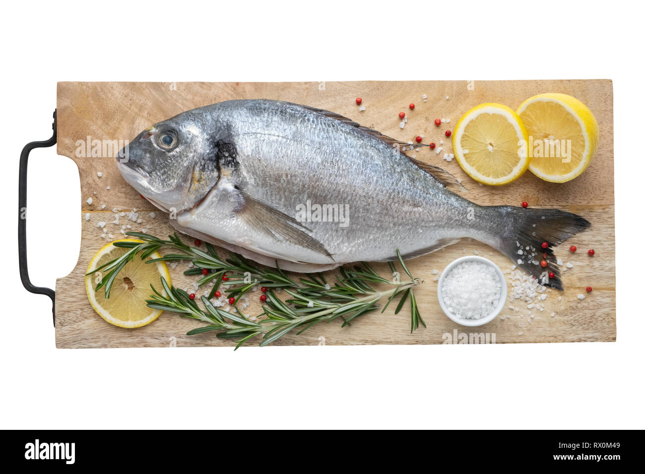 Fresh dorado fish with lemon slices, salt and rosemary on cutting board ...