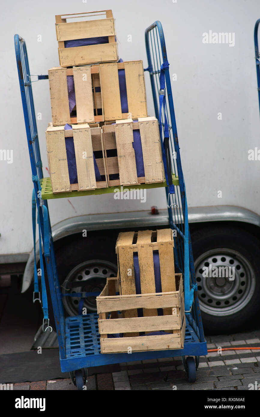 A trolley with empty wooden boxes is next to the truck of a dealer at ...