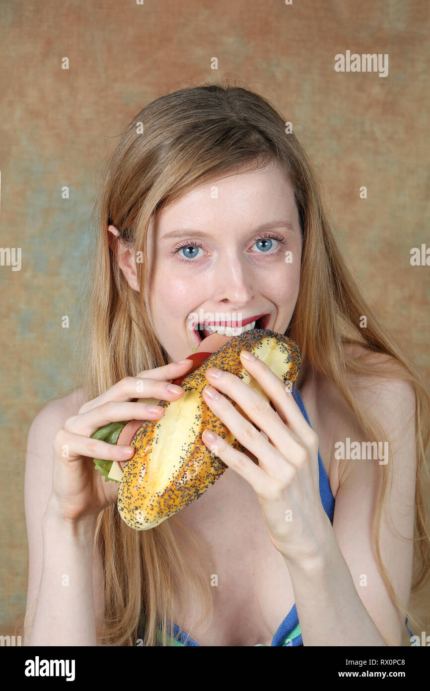 Young blue eyed woman smiling while eating a sandwich Stock Photo - Alamy