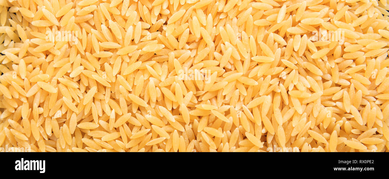 Italian food. Uncooked dry orzo pasta risoni texture background, banner ...