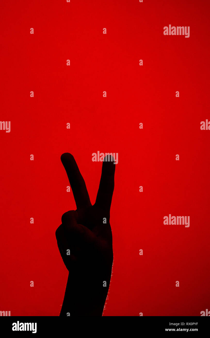 The soft hand showing the victory sign is isolated on a red background ...