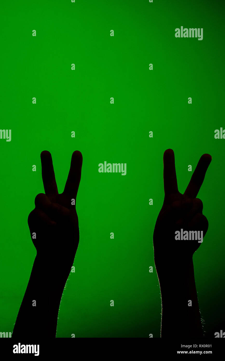 Two beautiful hands showing a victory sign isolated on a green ...
