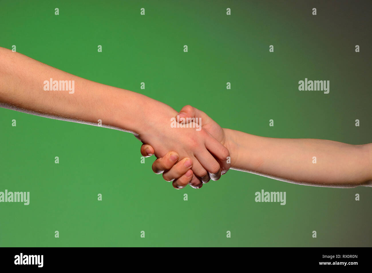 Two hands handshake, isolated on a green background, symbolizing ...