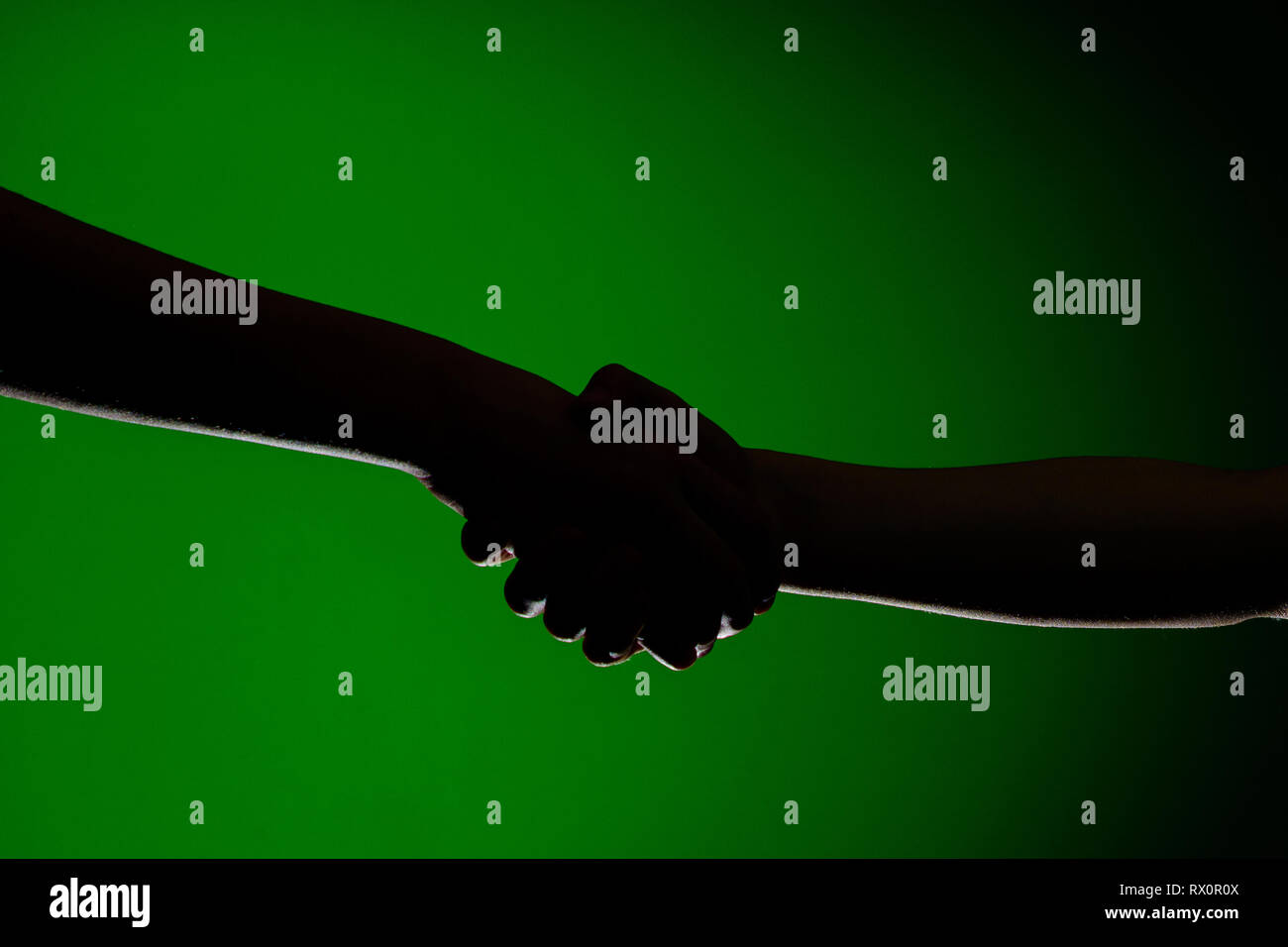 Two hands handshake, isolated on a green background, symbolizing ...