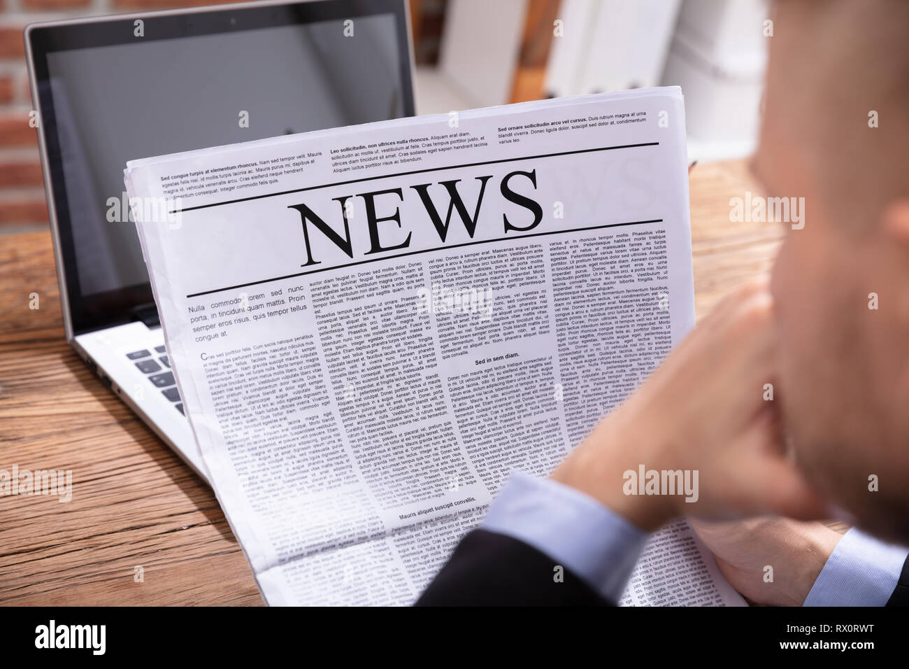 Close-up Of A Man's Hand Holding Newspaper Over Wooden Desk Stock Photo ...