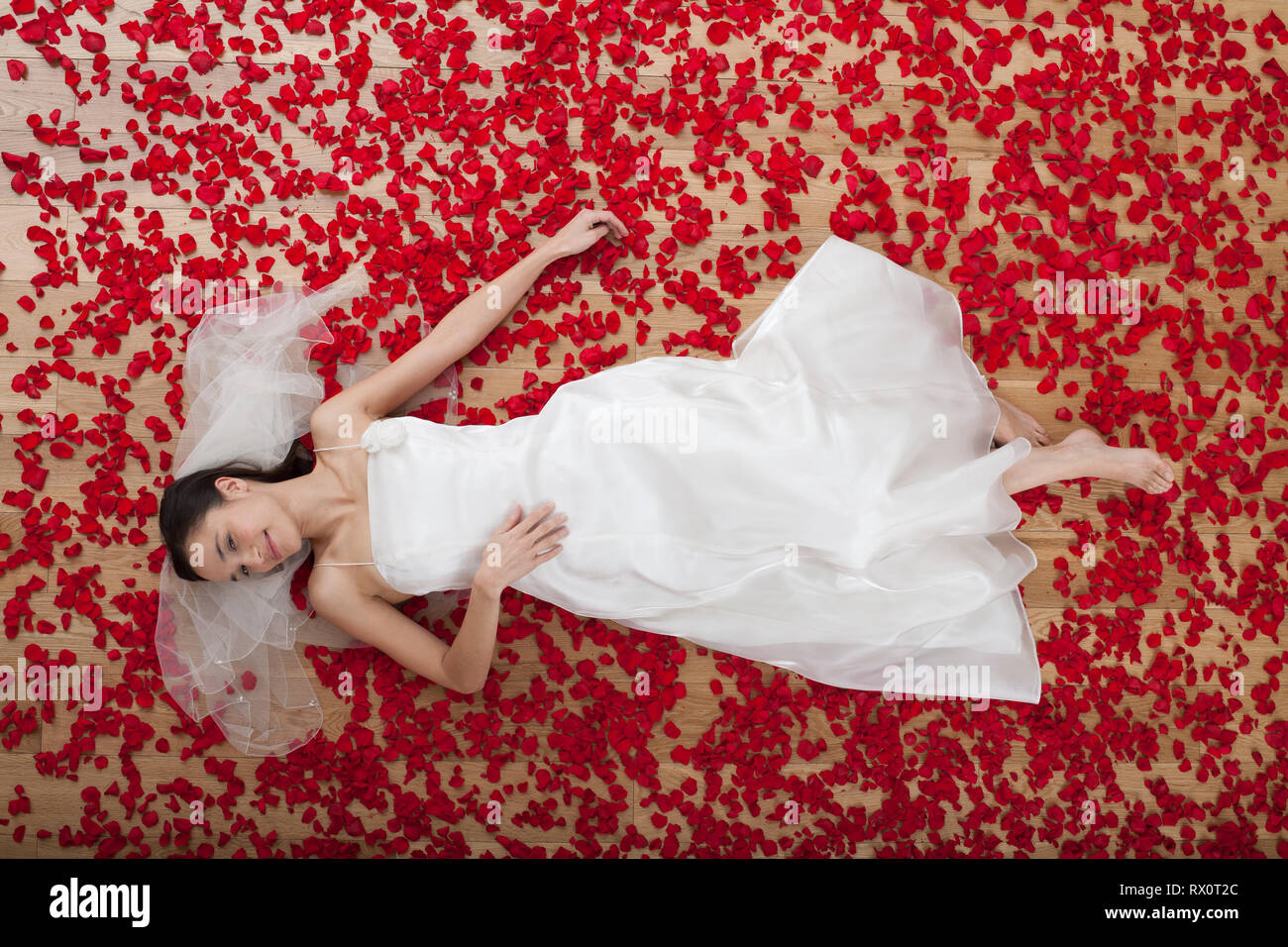 Young woman lying on floor with rose petals Stock Photo - Alamy