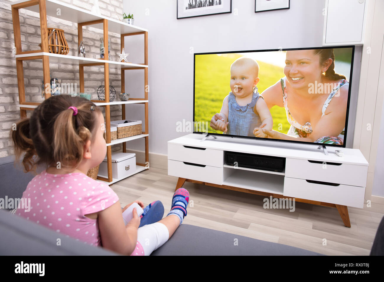 Close-up Of Innocent Girl Sitting On Sofa Watching Television In Living ...