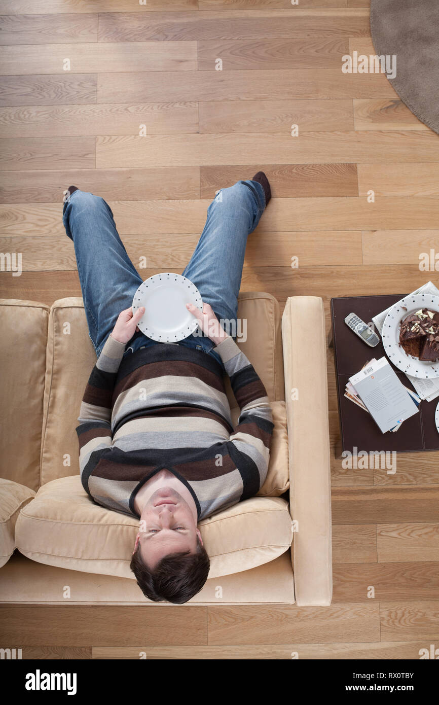 Young man holding an empty plate in a living room Stock Photo - Alamy