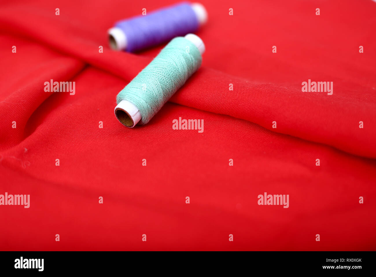 Picture of two sewing thread on the red cloth Stock Photo - Alamy