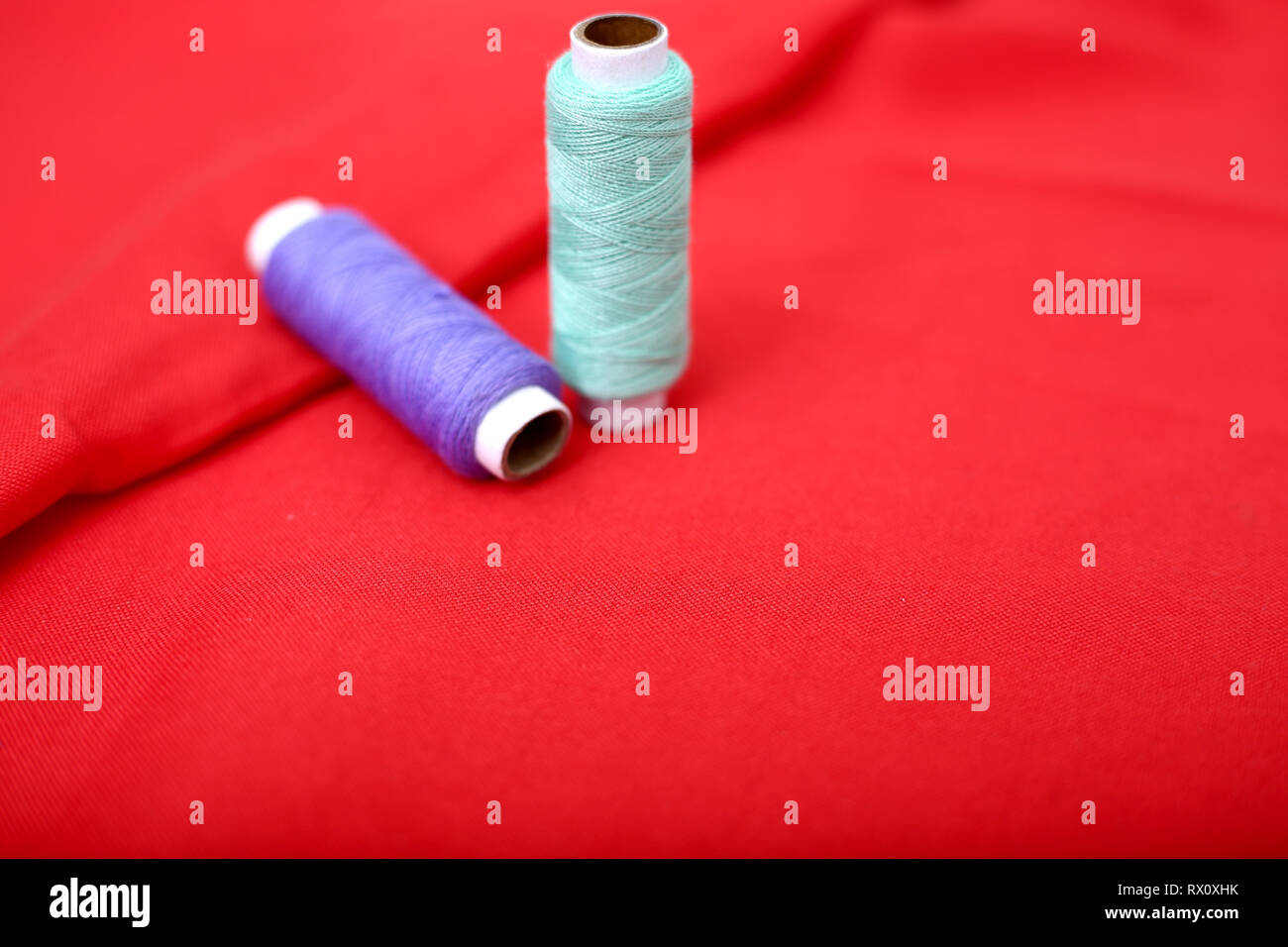 Spool of sewing thread on the red cloth Stock Photo - Alamy