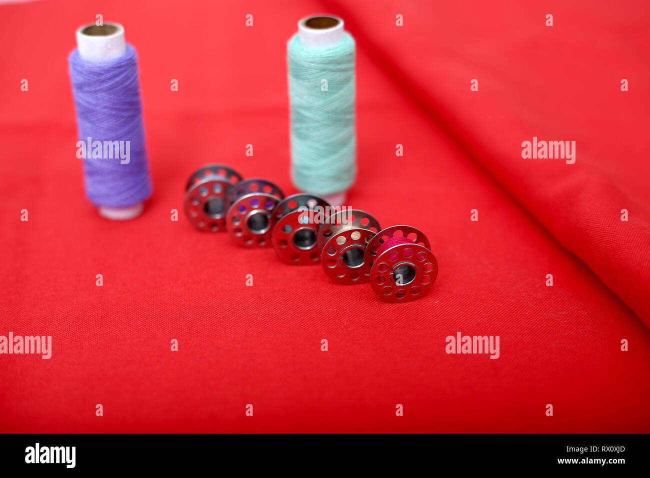 Picture of two sewing thread and bobbin on the red cloth Stock Photo ...