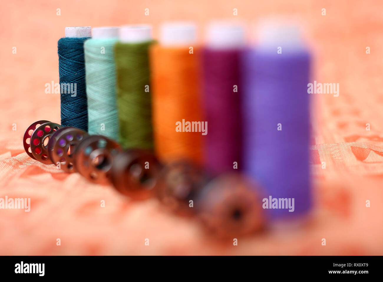 Spool of sewing thread with bobbin on the orange cloth Stock Photo - Alamy
