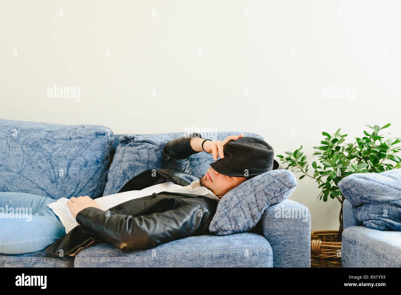 Young tired millennial man lying on a couch napping Stock Photo - Alamy
