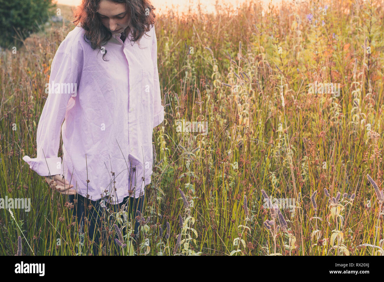 Man looking down while standing on grassy field during sunset Stock ...