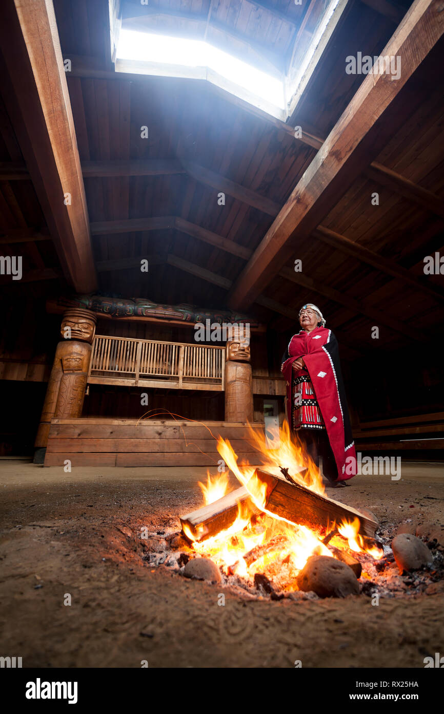 A first nations elder dressed in her traditional regalia stands beside ...