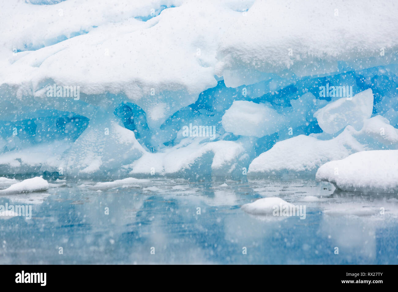 A grounded iceberg is slowly covered in snow from a summer storm near ...