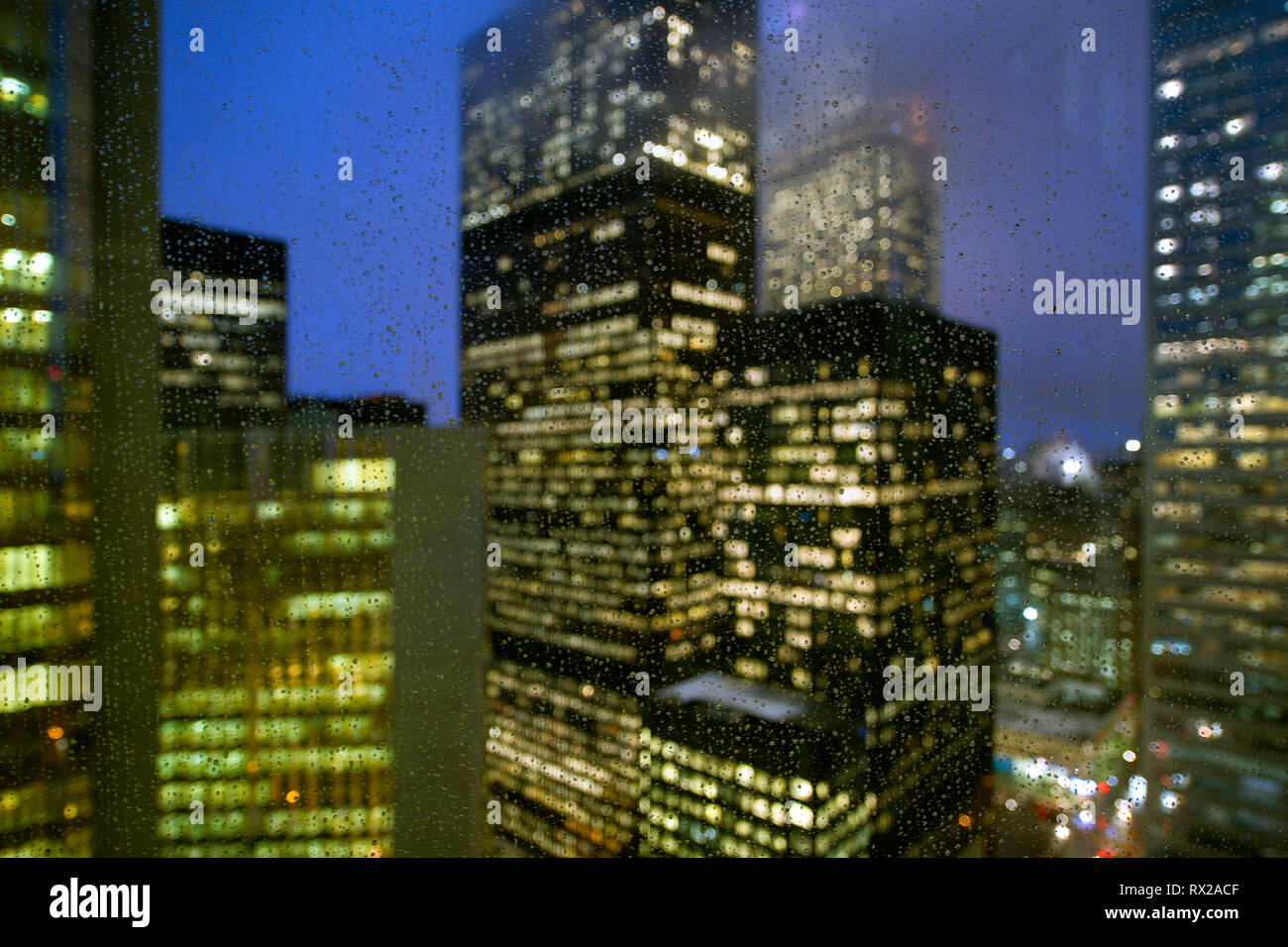 Inside looking out of a rain dappled window toward skyscrapers in the ...