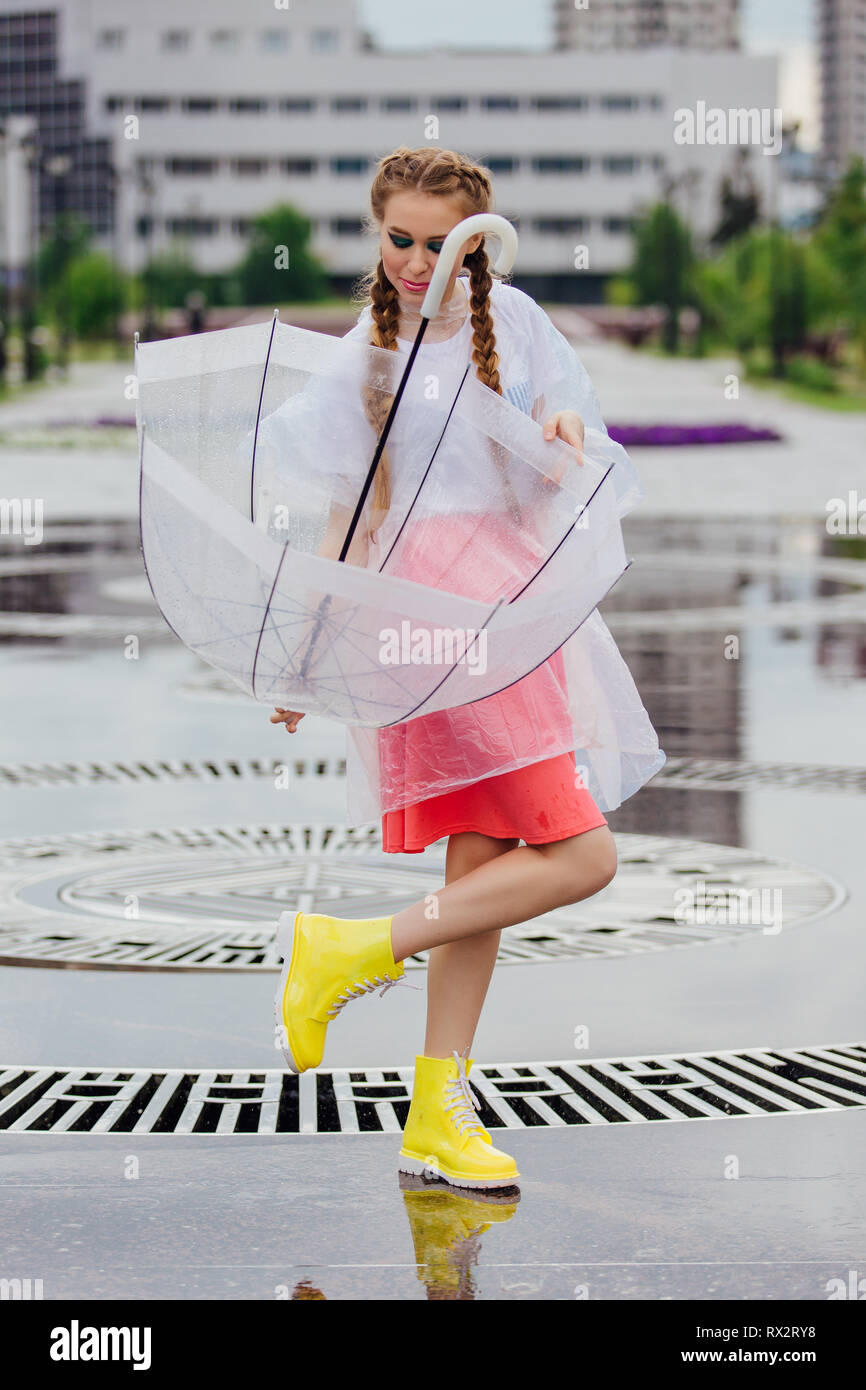 Young pretty girl with two braids in yellow boots and with transparent ...