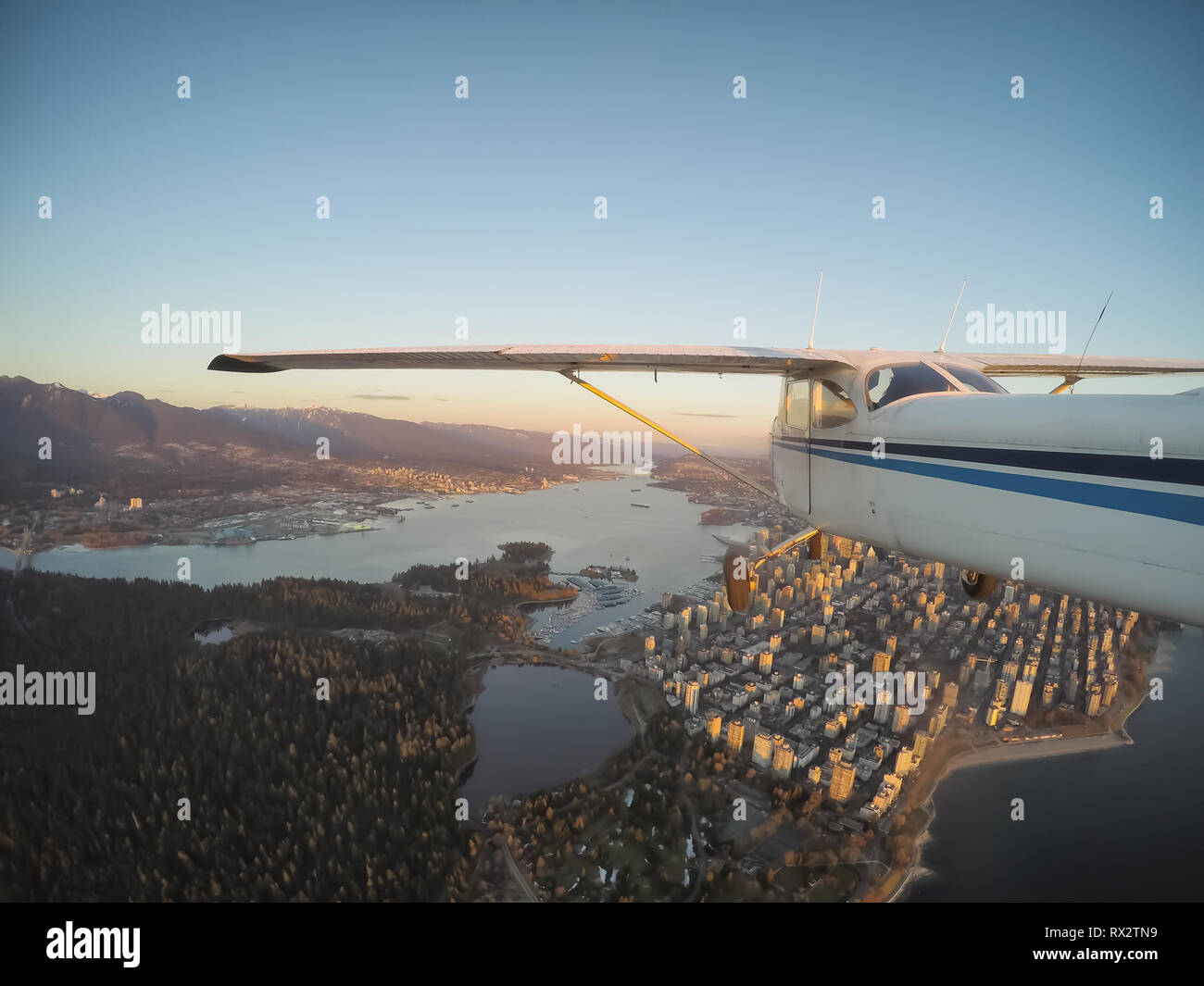 Small airplane flying over Downtown City during a vibrant sunset. Taken ...