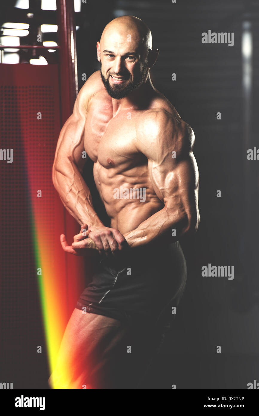 Handsome Young Man Standing Strong In The Gym And Flexing Muscles ...