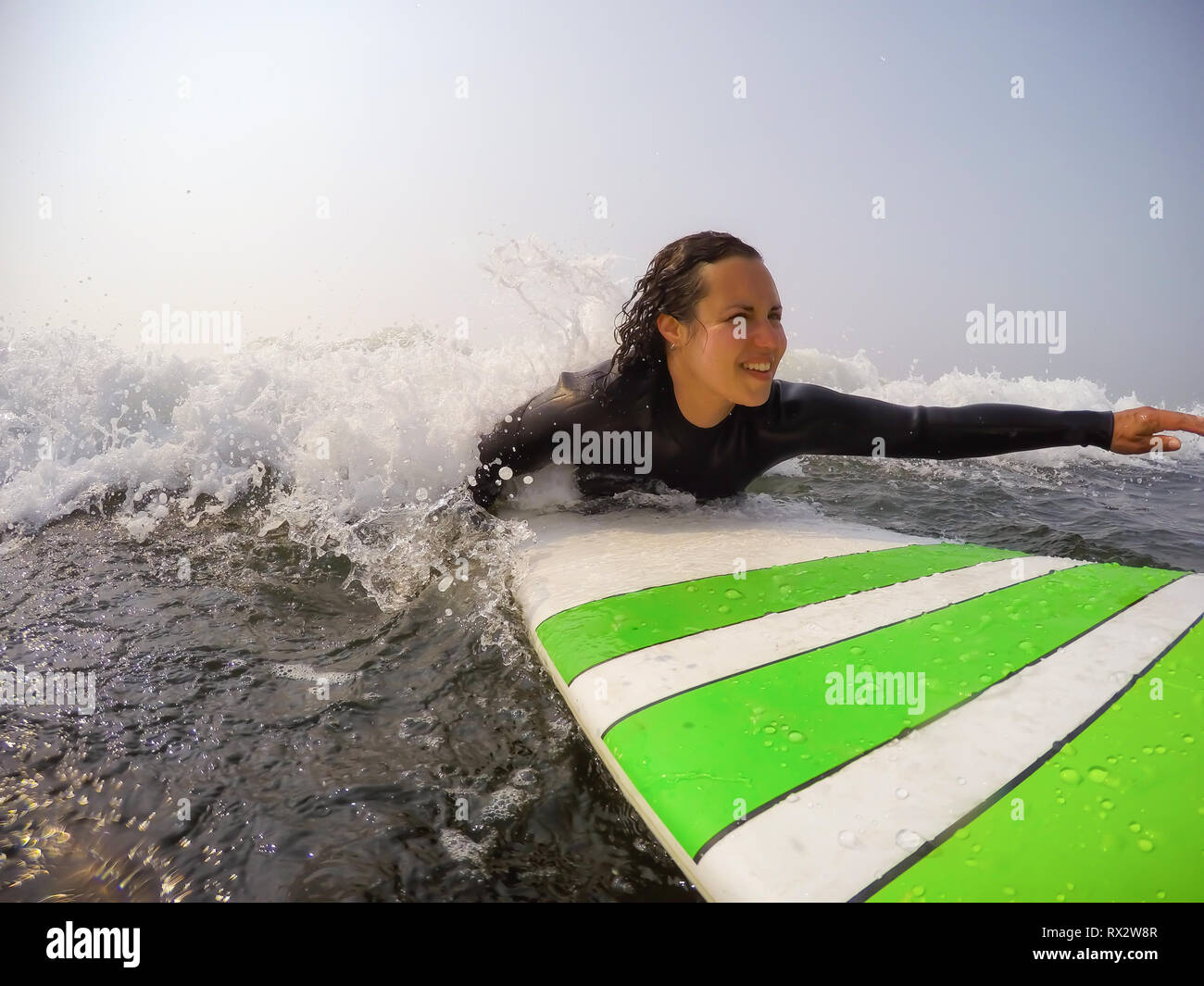 Female beginner surfer is learning how to surf in the Pacific Ocean ...