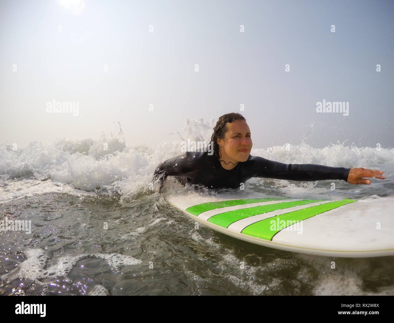 Female beginner surfer is learning how to surf in the Pacific Ocean ...