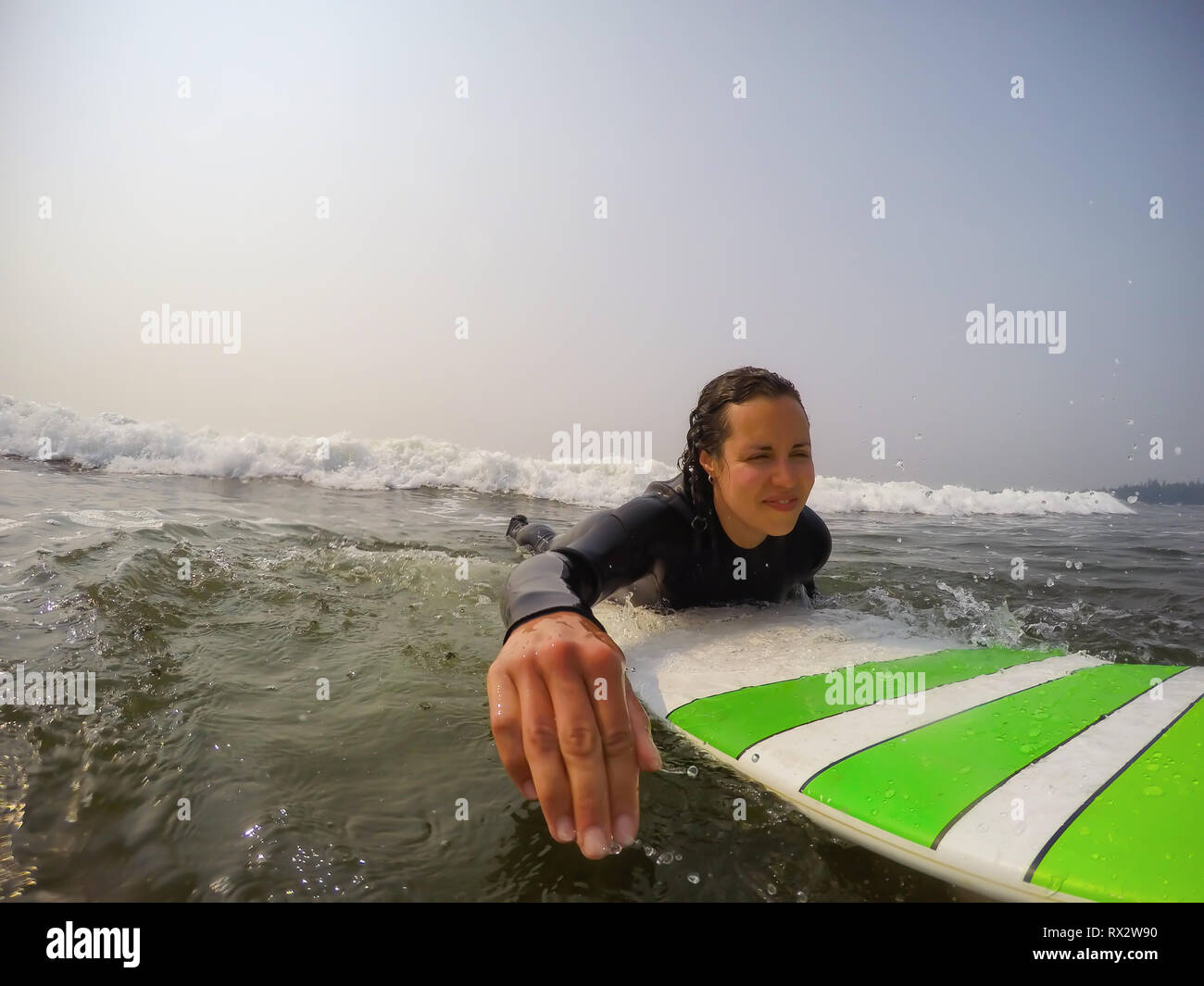 Female beginner surfer is learning how to surf in the Pacific Ocean ...