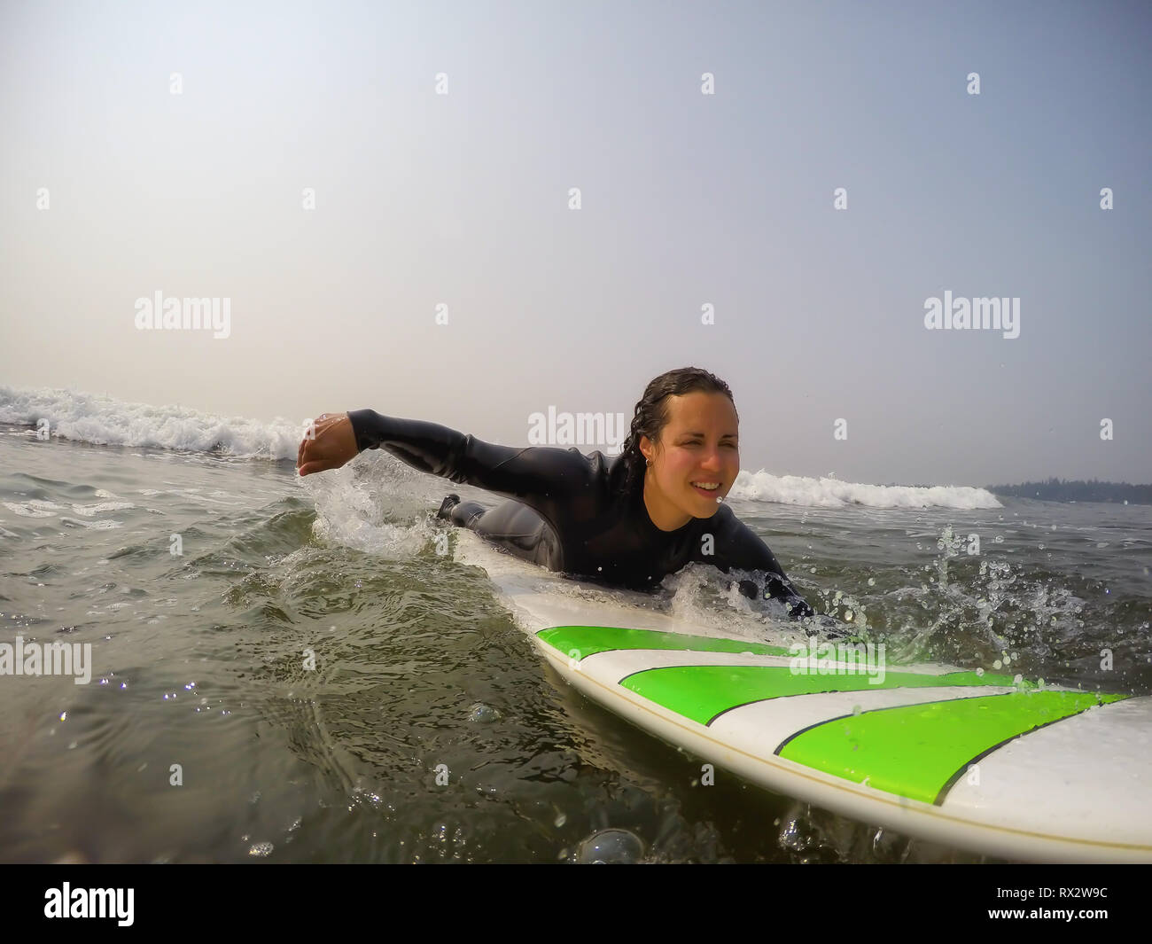 Female beginner surfer is learning how to surf in the Pacific Ocean ...