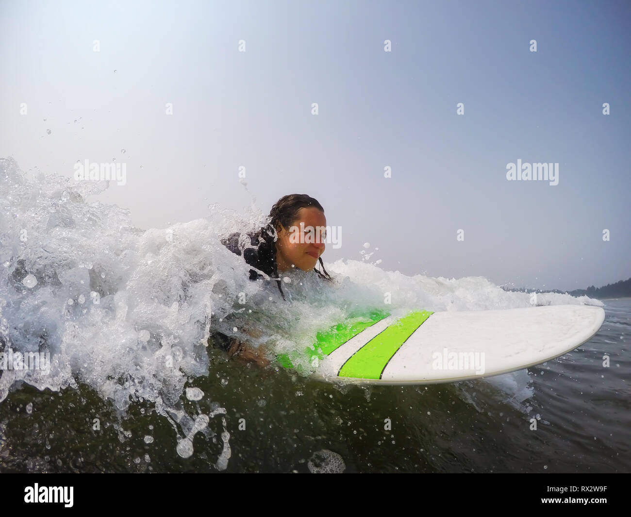 Female beginner surfer is learning how to surf in the Pacific Ocean ...
