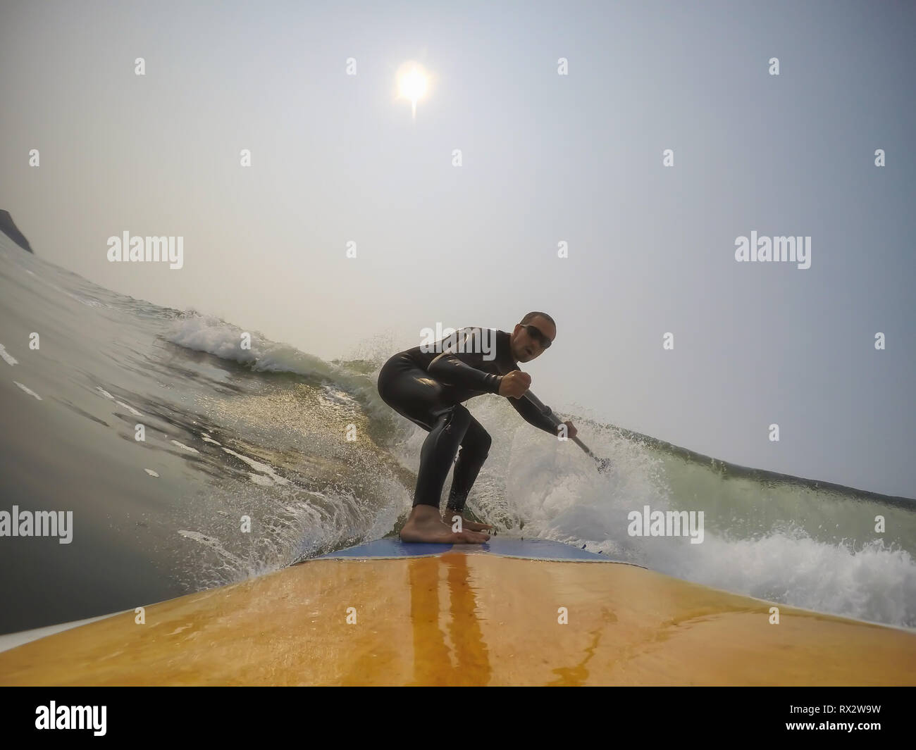 Man paddle surfer is riding a wave in the Pacific Ocean. Taken in ...
