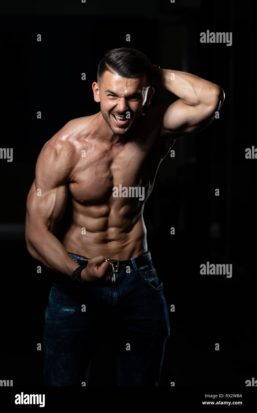 Healthy Young Man In Jeans Standing Strong In The Gym And Flexing ...