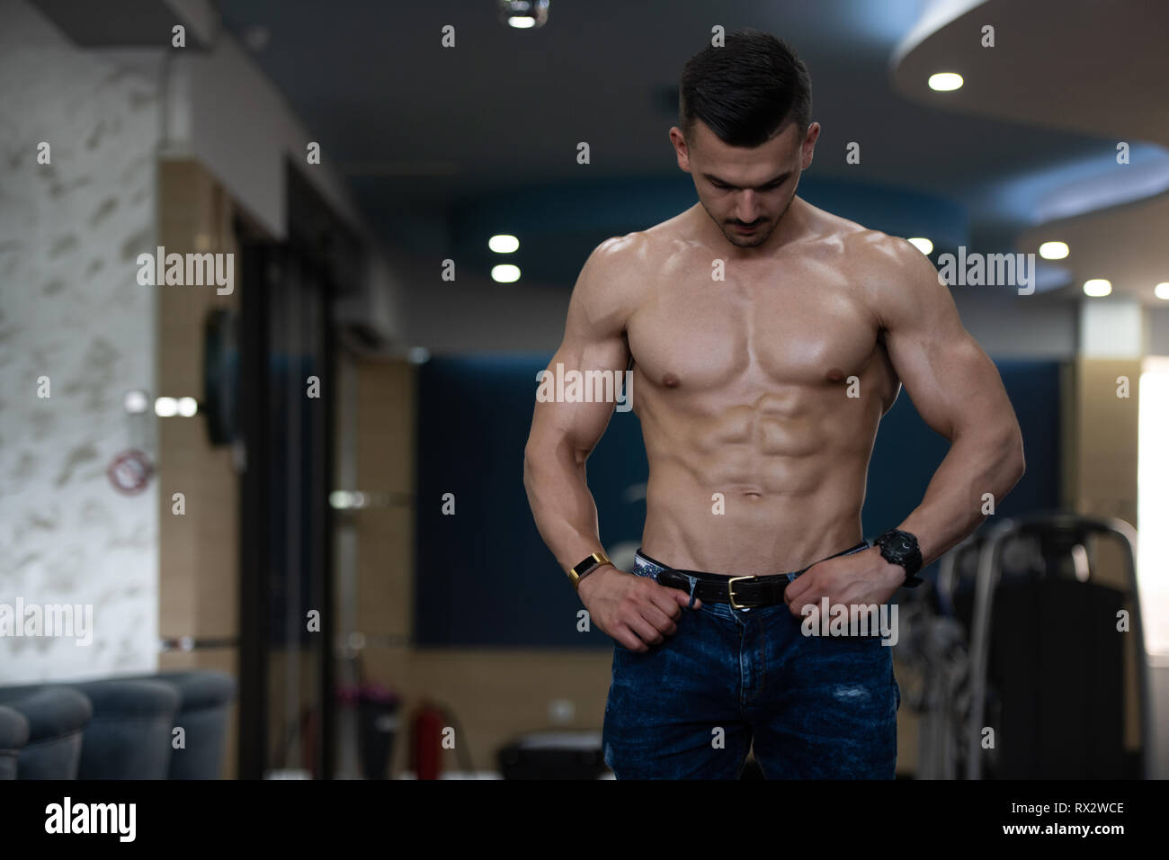 Healthy Young Man In Jeans Standing Strong In The Gym And Flexing ...