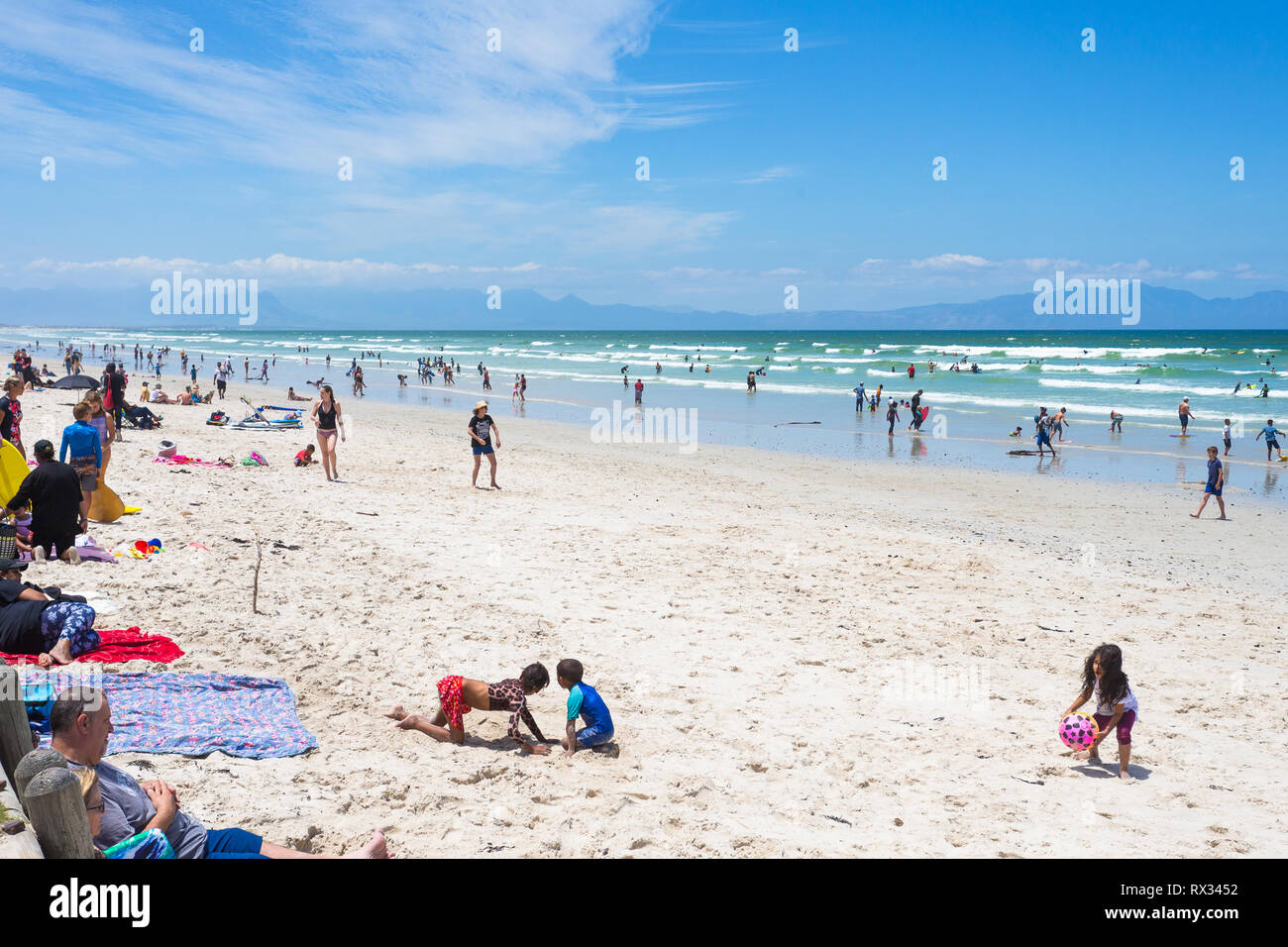 a busy beach day with crowds of beachgoers enjoying themselves on a hot ...