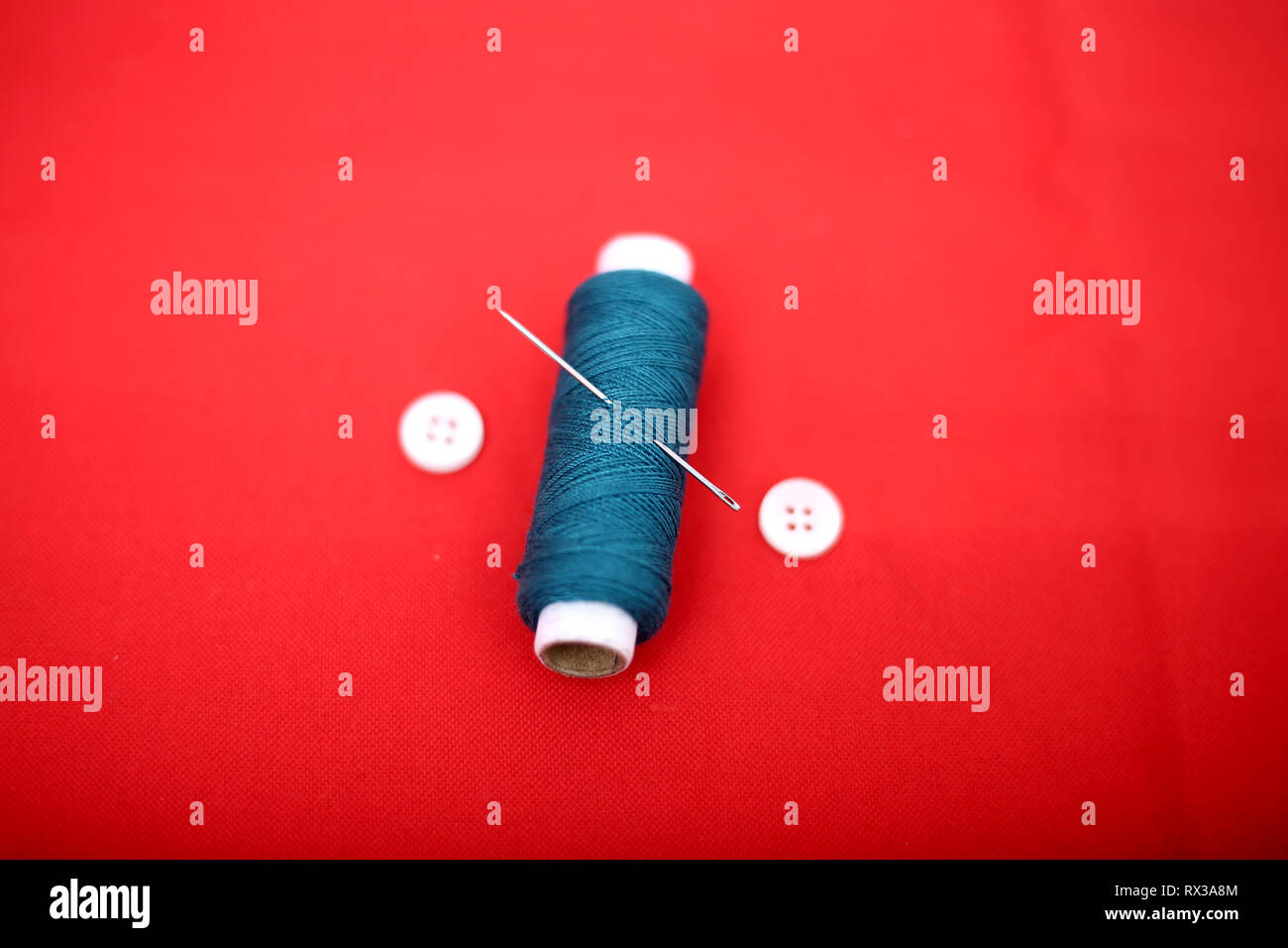 Picture of sewing thread with needle and button. Isolated on the red ...