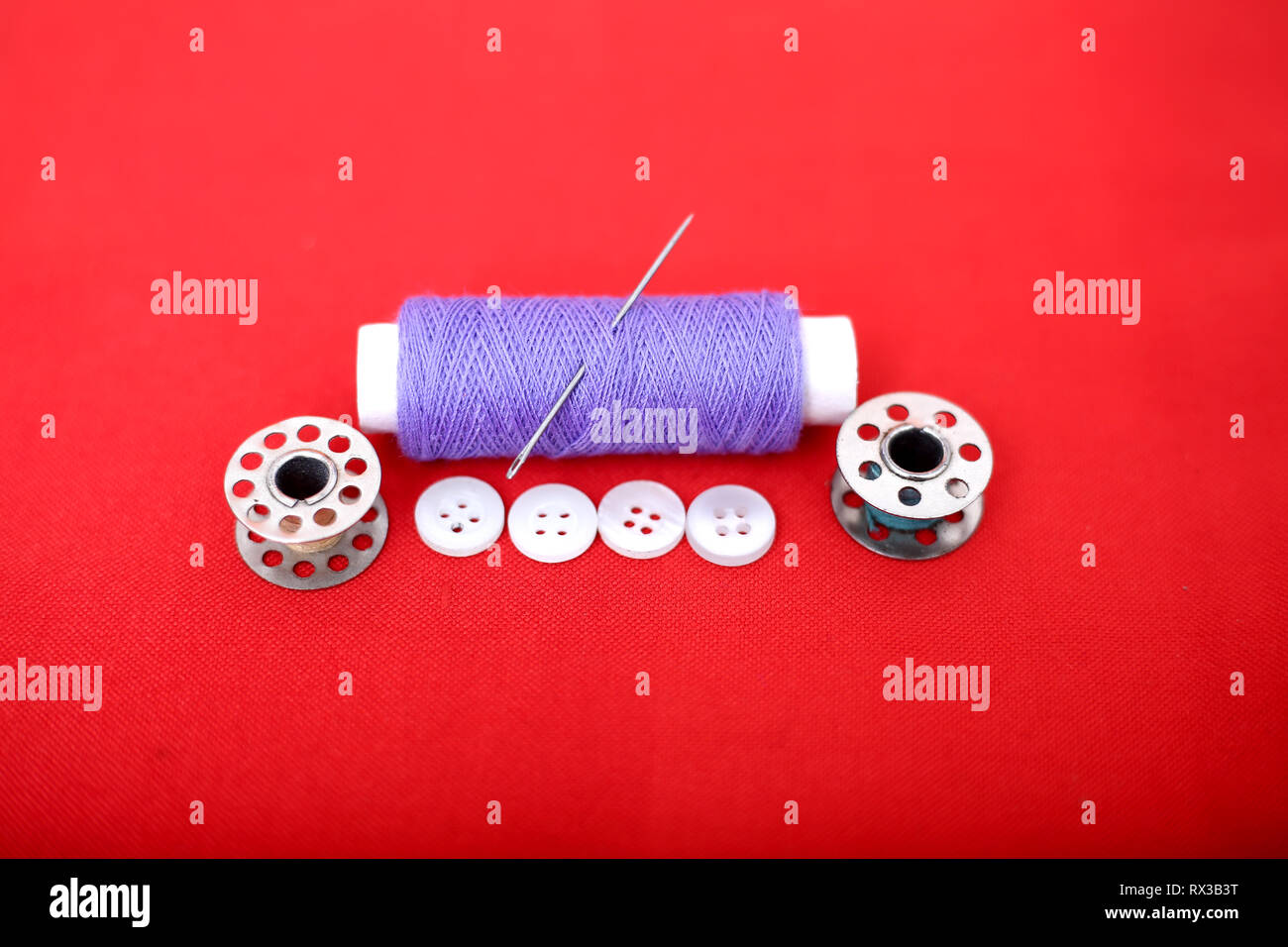 Picture of spool thread, needle, bobbin and button. Isolated on the red ...