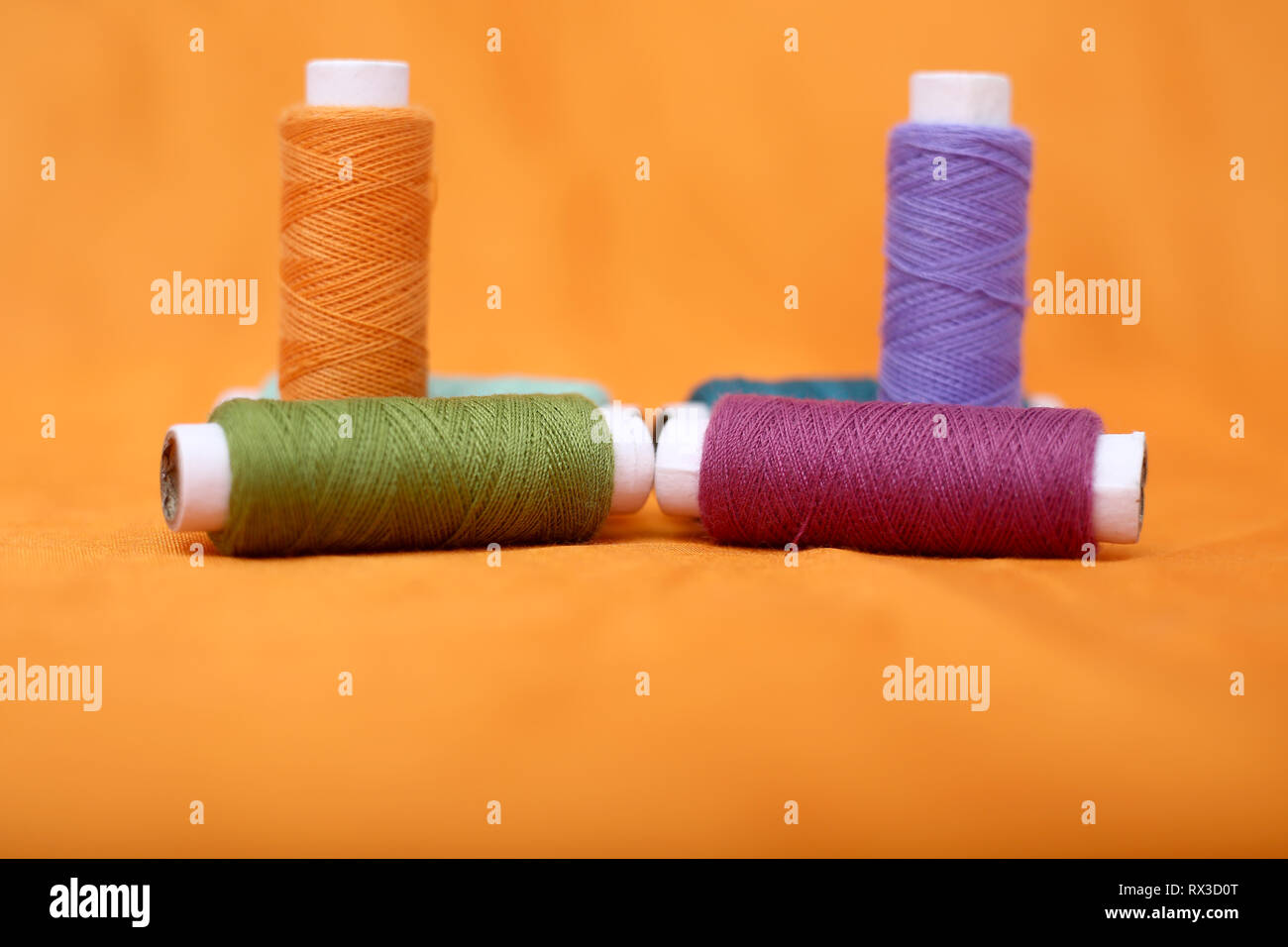 Picture of colored sewing thread. Isolated on the yellow background ...