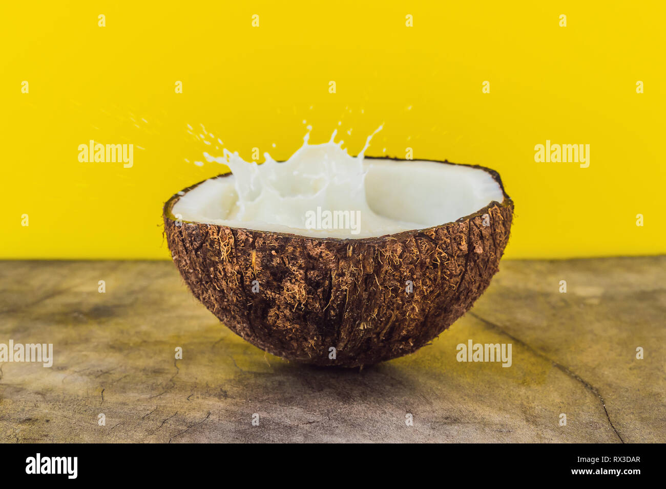 Coconut fruit and milk splash inside it on yellow background Stock ...