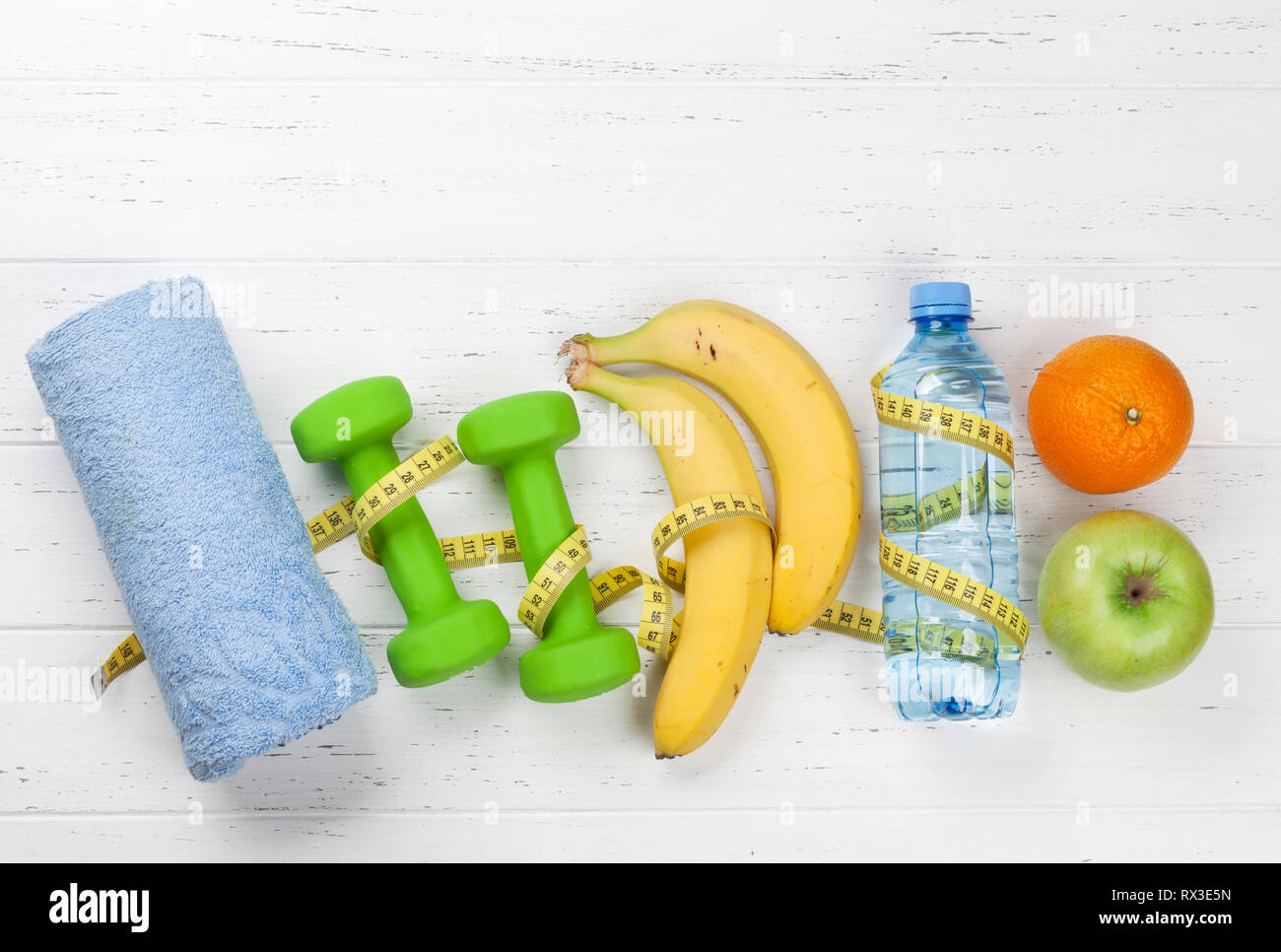 Fitness and healthy food concept. Dumbbells, fruits and drink bottle on ...