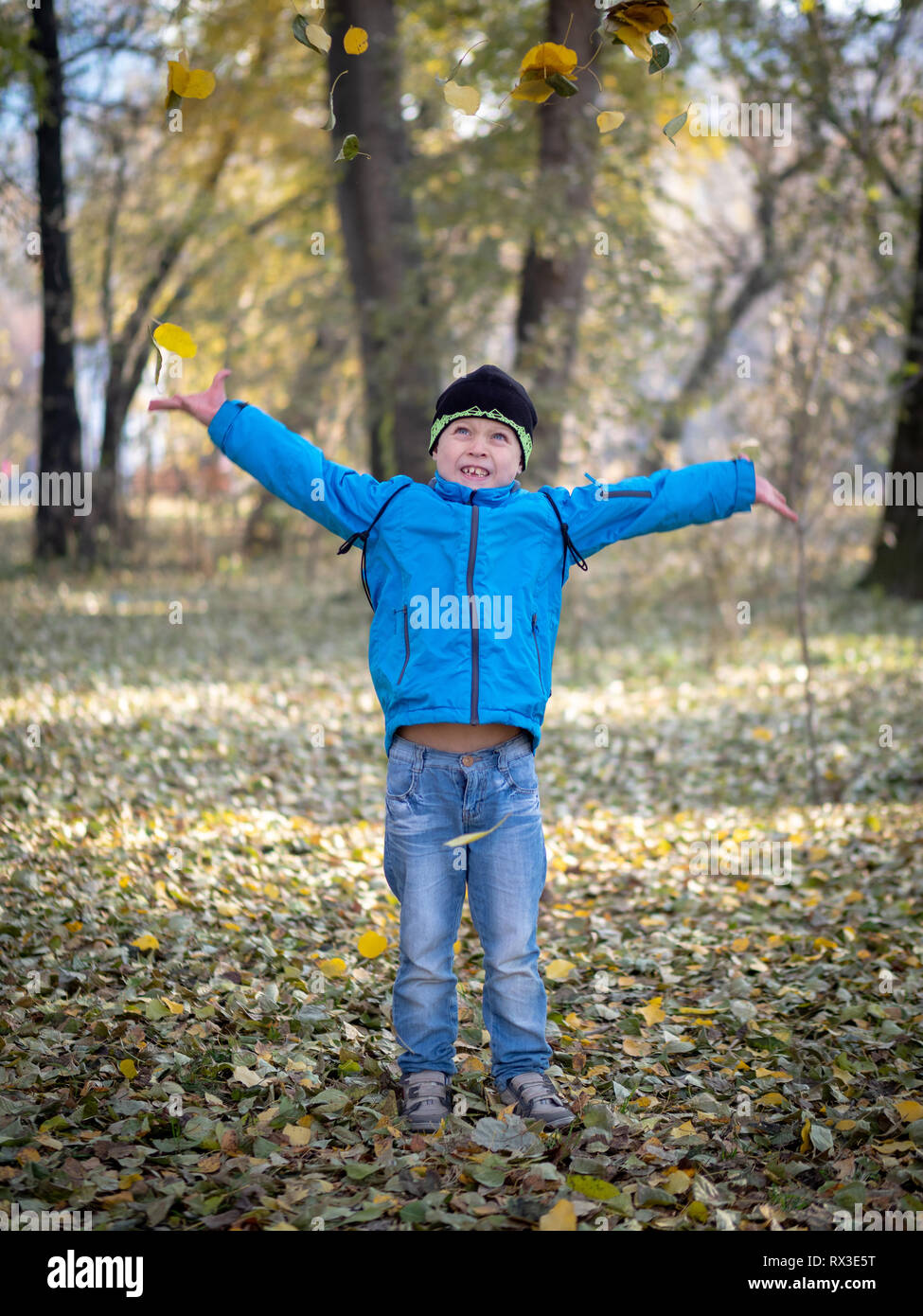 Happy boy throws yellowed dry leaves in autumn park Stock Photo - Alamy