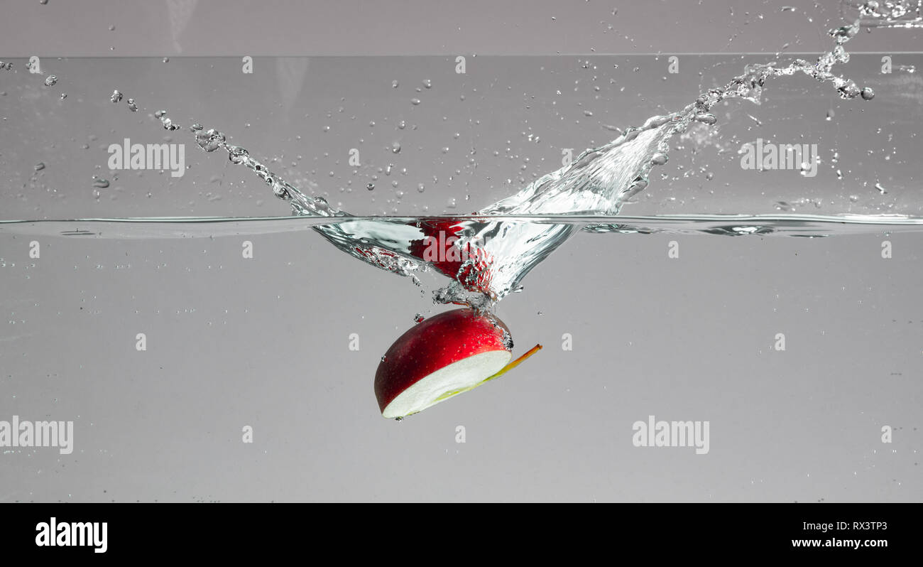 Red apple slice falls into water and creates beautiful air bubbles and ...