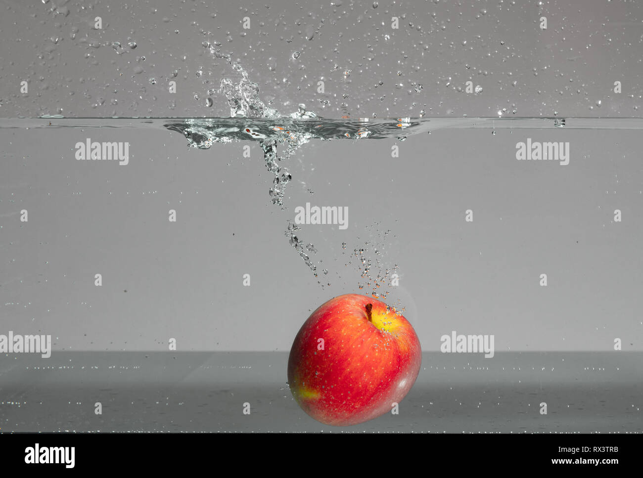 Red yellow apple falls into water and creates beautiful air bubbles and ...