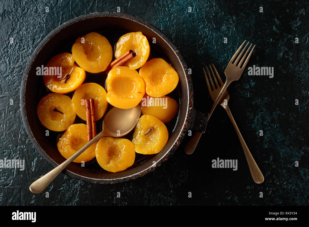 Peach dessert with cinnamon and cloves on a dark background, top view ...