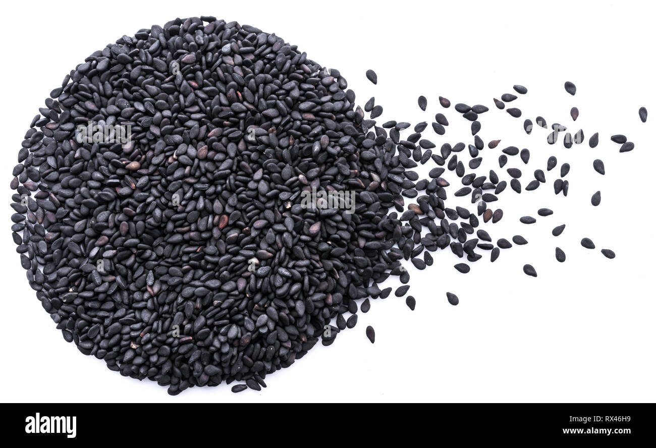 Black sesame seeds arranged in shape of circle on white background. Top ...