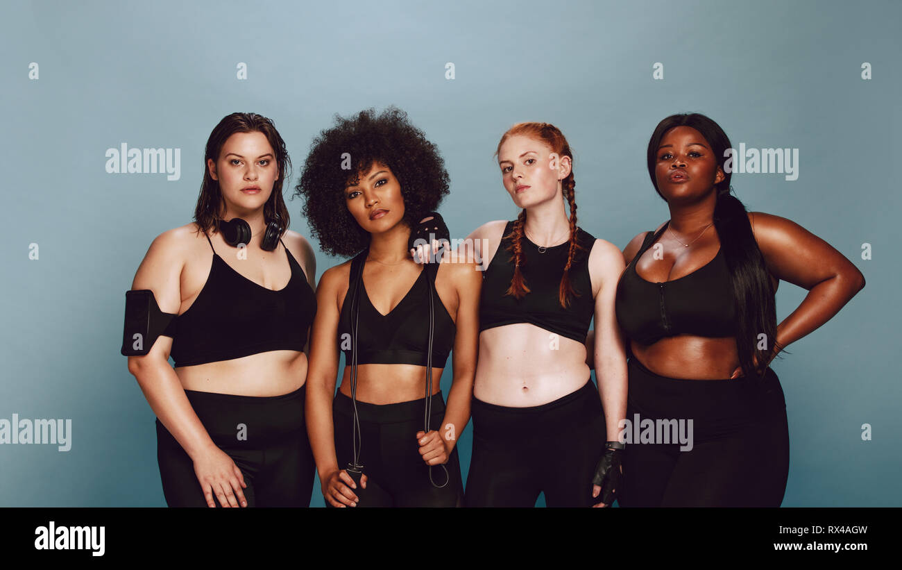 Portrait of mixed race women standing together against grey background ...