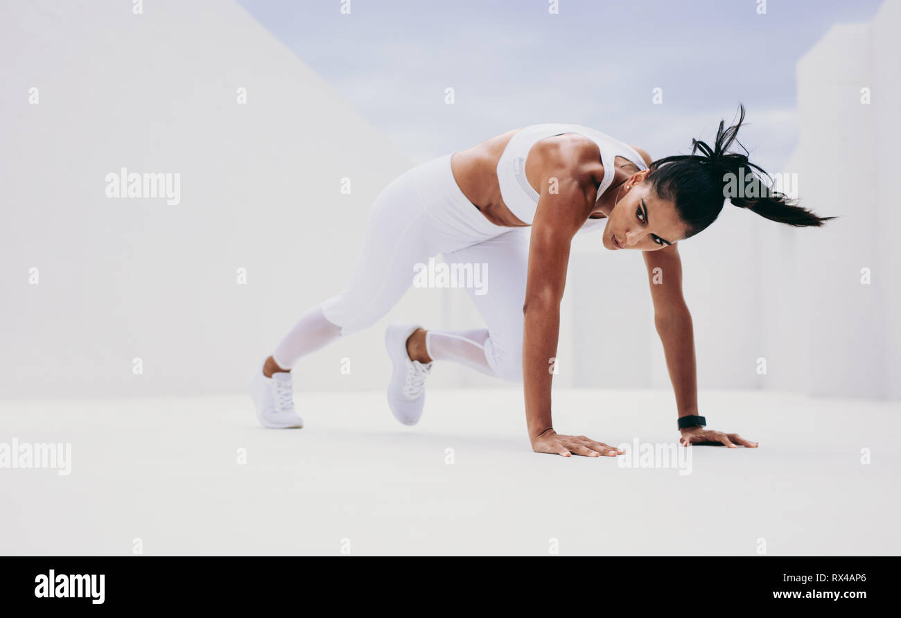 Athletic woman in push up position bringing her leg forward. Woman ...