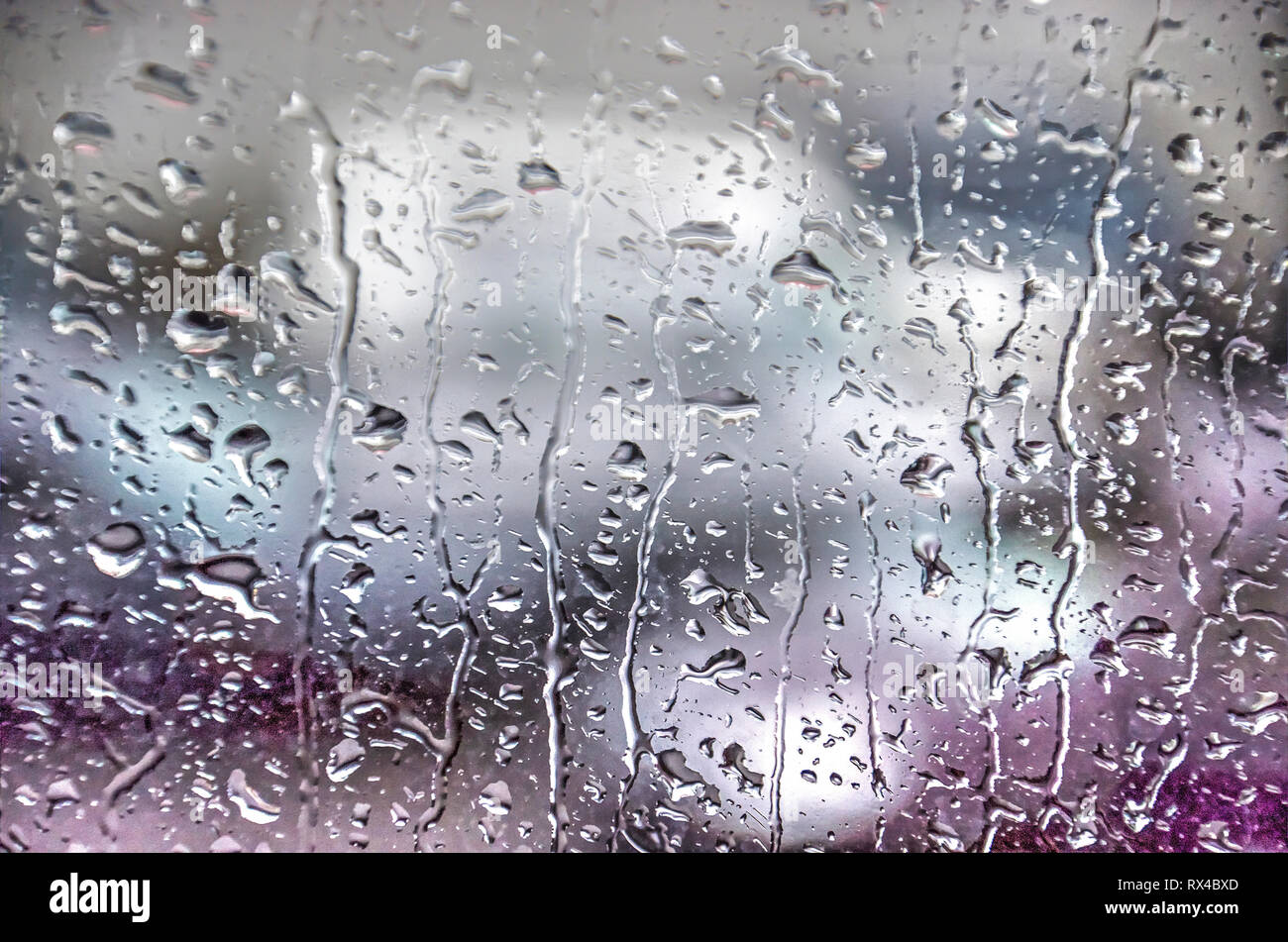 Raindrops creating a pattern on a glass window, with unrecognizable ...