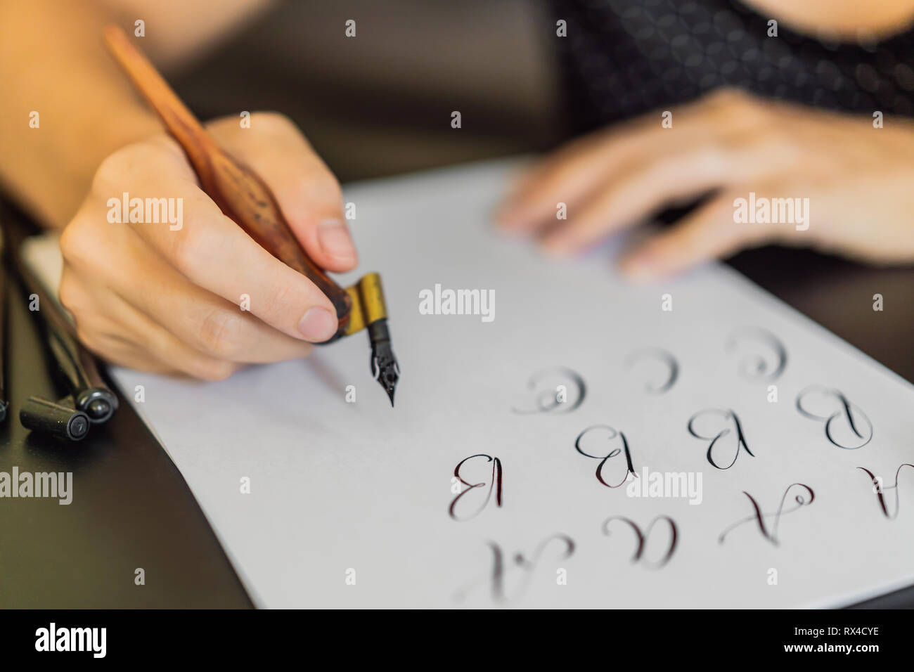 Calligrapher hands writes phrase on white paper. Inscribing ornamental ...